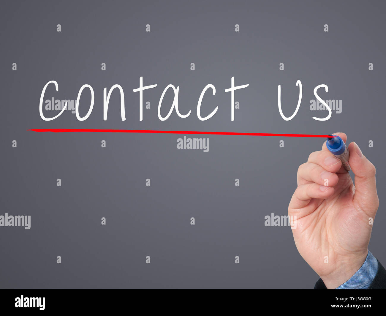 Businessman writing contact us against grey background. Stock Image ...