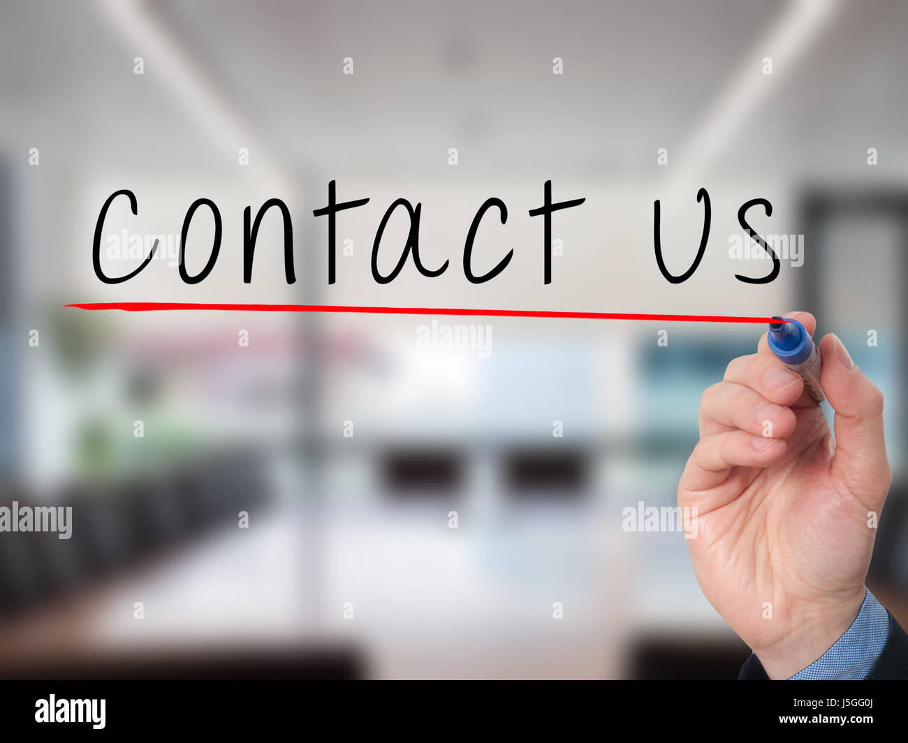 Businessman writing contact us against office background. Stock Image ...