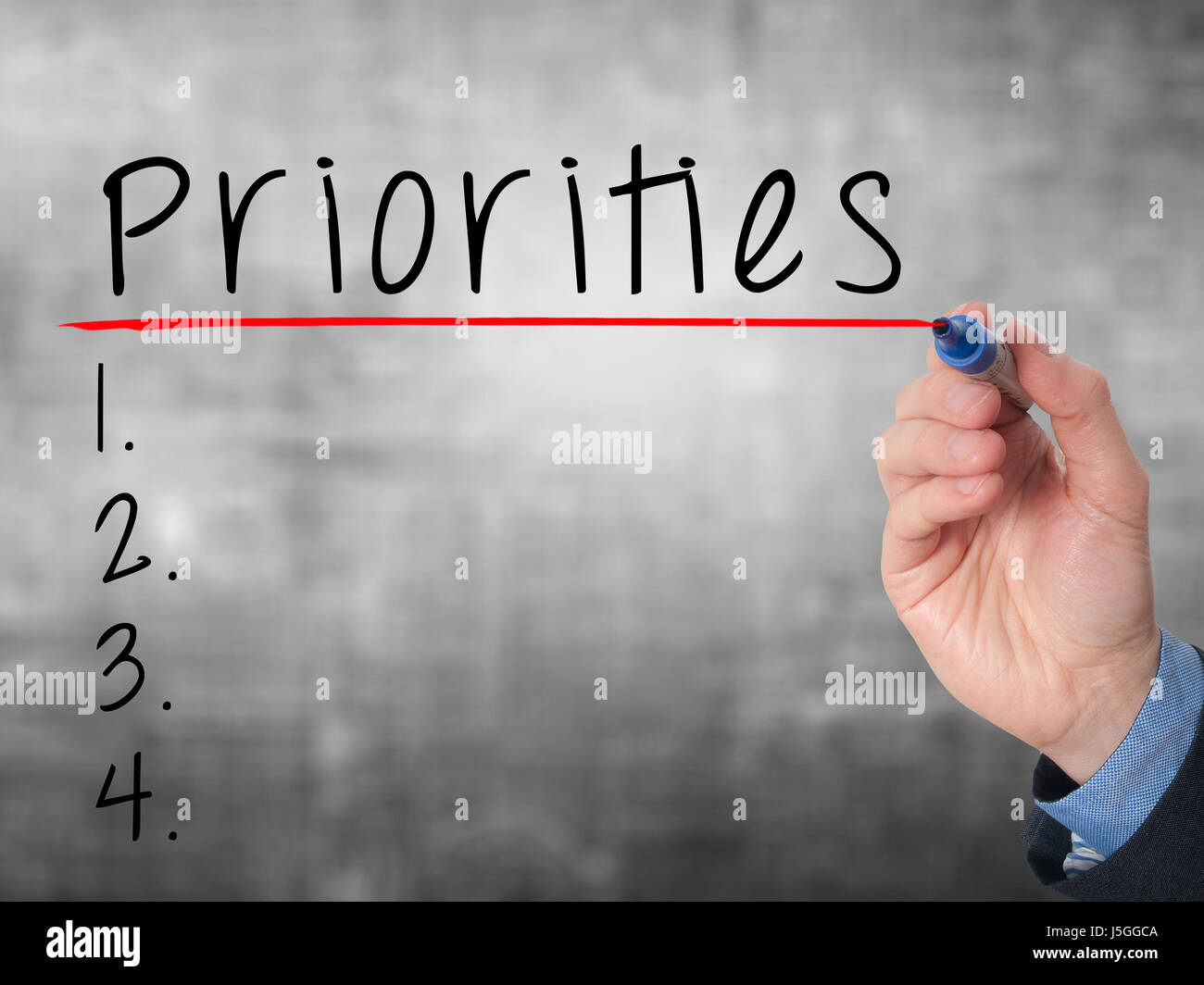 Business man hand writing Priorities list with marker isolated on grey ...