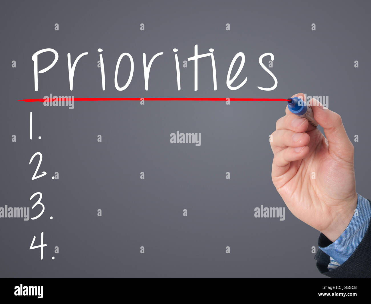 Business man hand writing Priorities list with marker isolated on grey ...