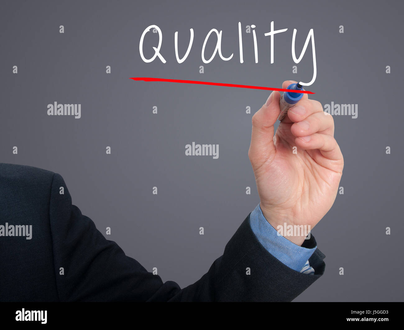 Businessman hand writing quality in the air. Grey Stock Photo - Alamy