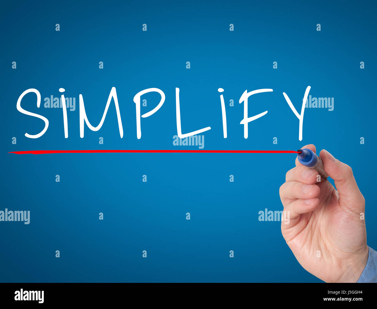 Businessman hand writing Simplify with marker on transparent wipe board ...