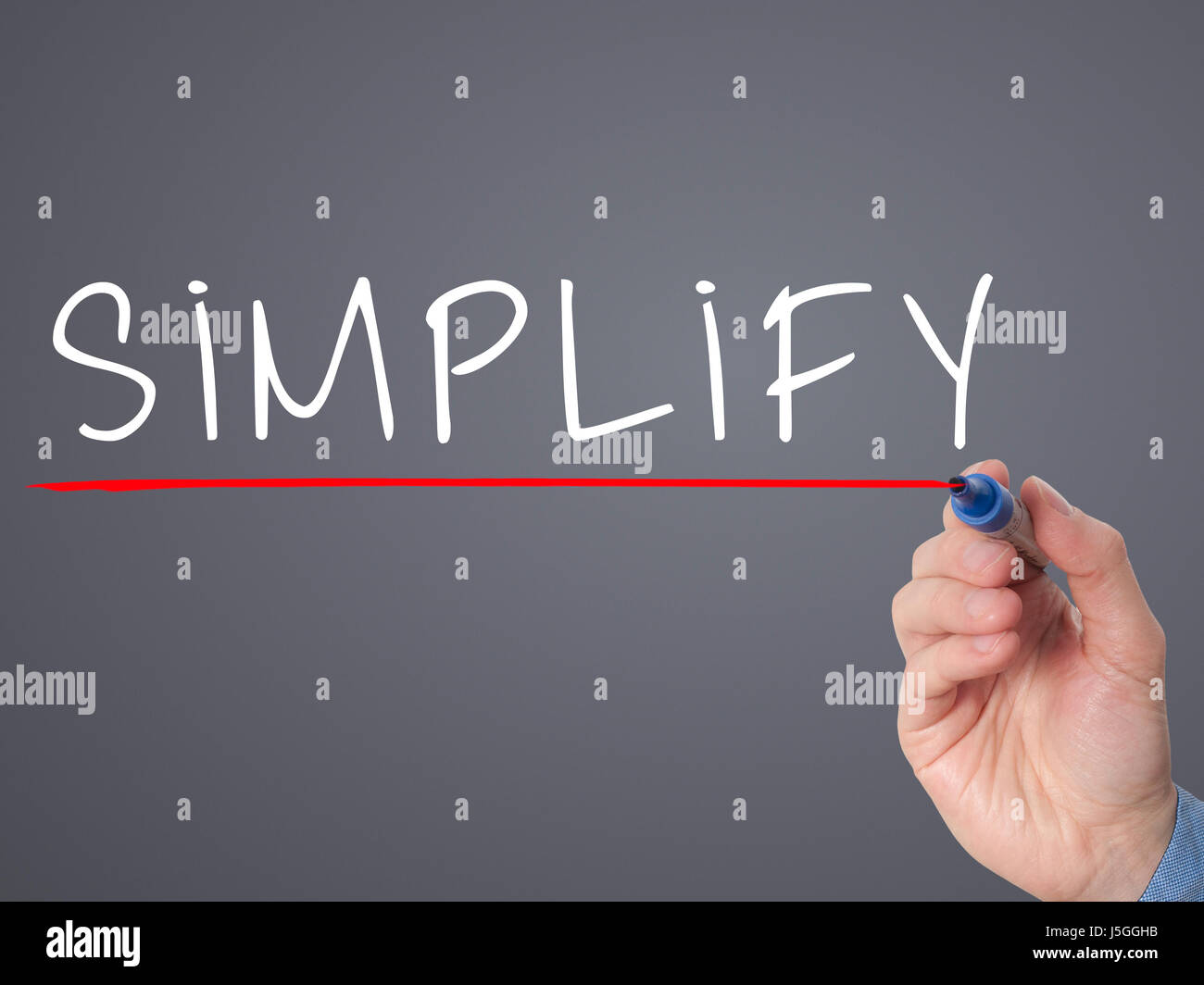 Businessman hand writing Simplify with marker on transparent wipe board ...