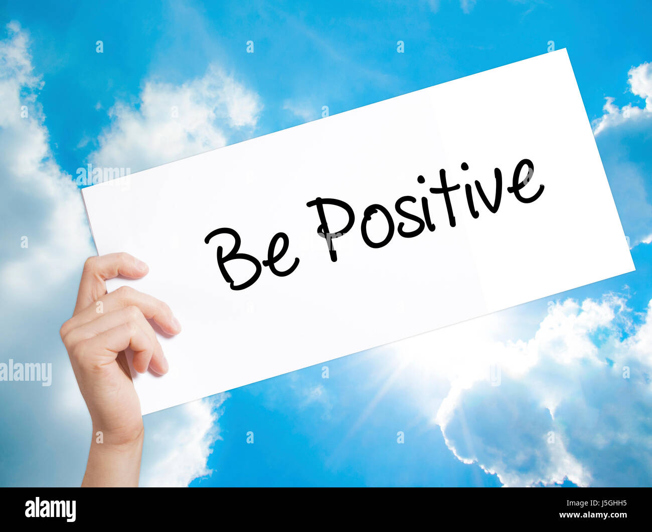 Be Positive Sign on white paper. Man Hand Holding Paper with text ...