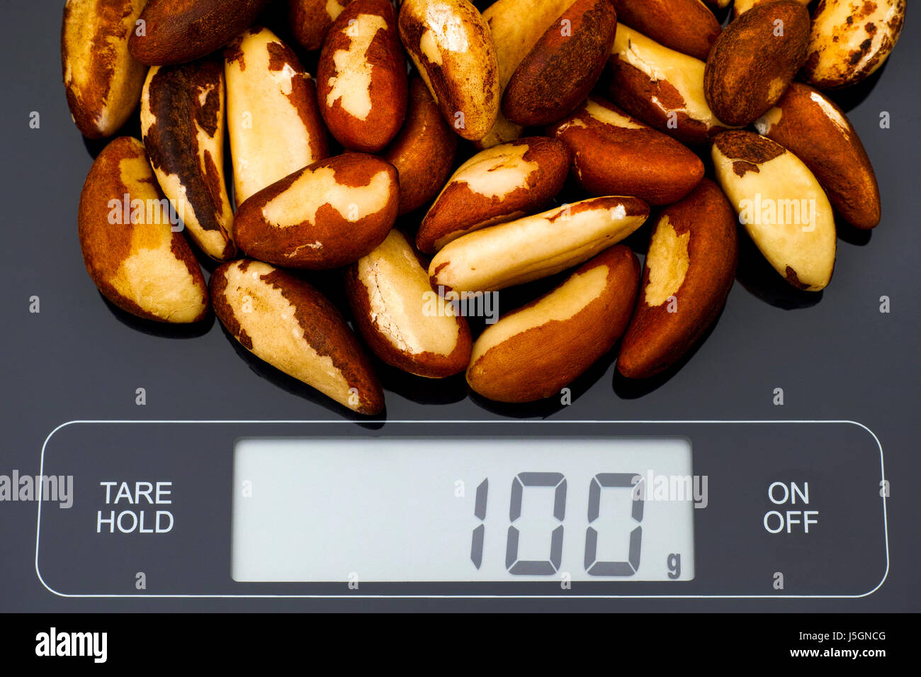 Brazil nuts on digital scale displaying 100 gram Stock Photo - Alamy