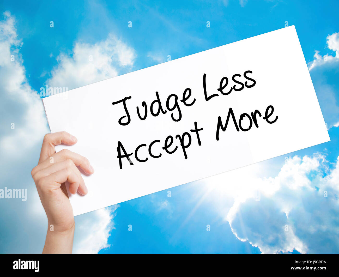 Judge Less Accept More Sign on white paper. Man Hand Holding Paper with ...
