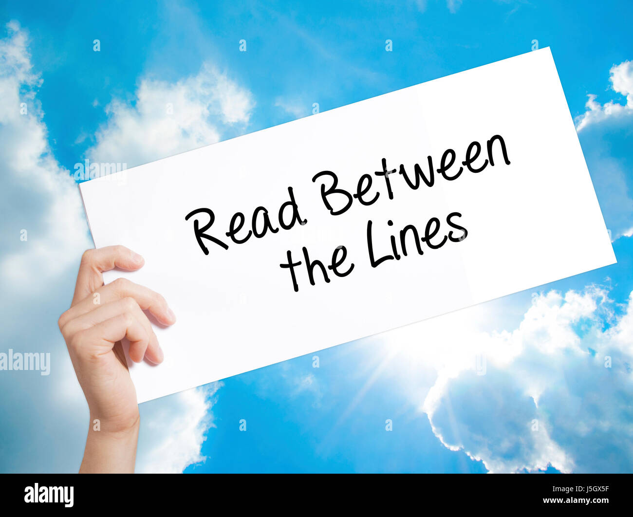 Read Between the Lines Sign on white paper. Man Hand Holding Paper with ...
