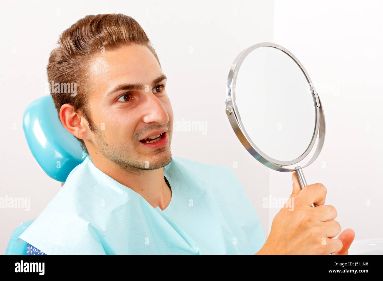 Surprised patient looking in the mirror after dental treatment Stock ...