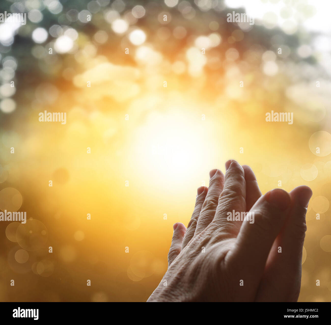 Hands together praying in bright sky Stock Photo - Alamy