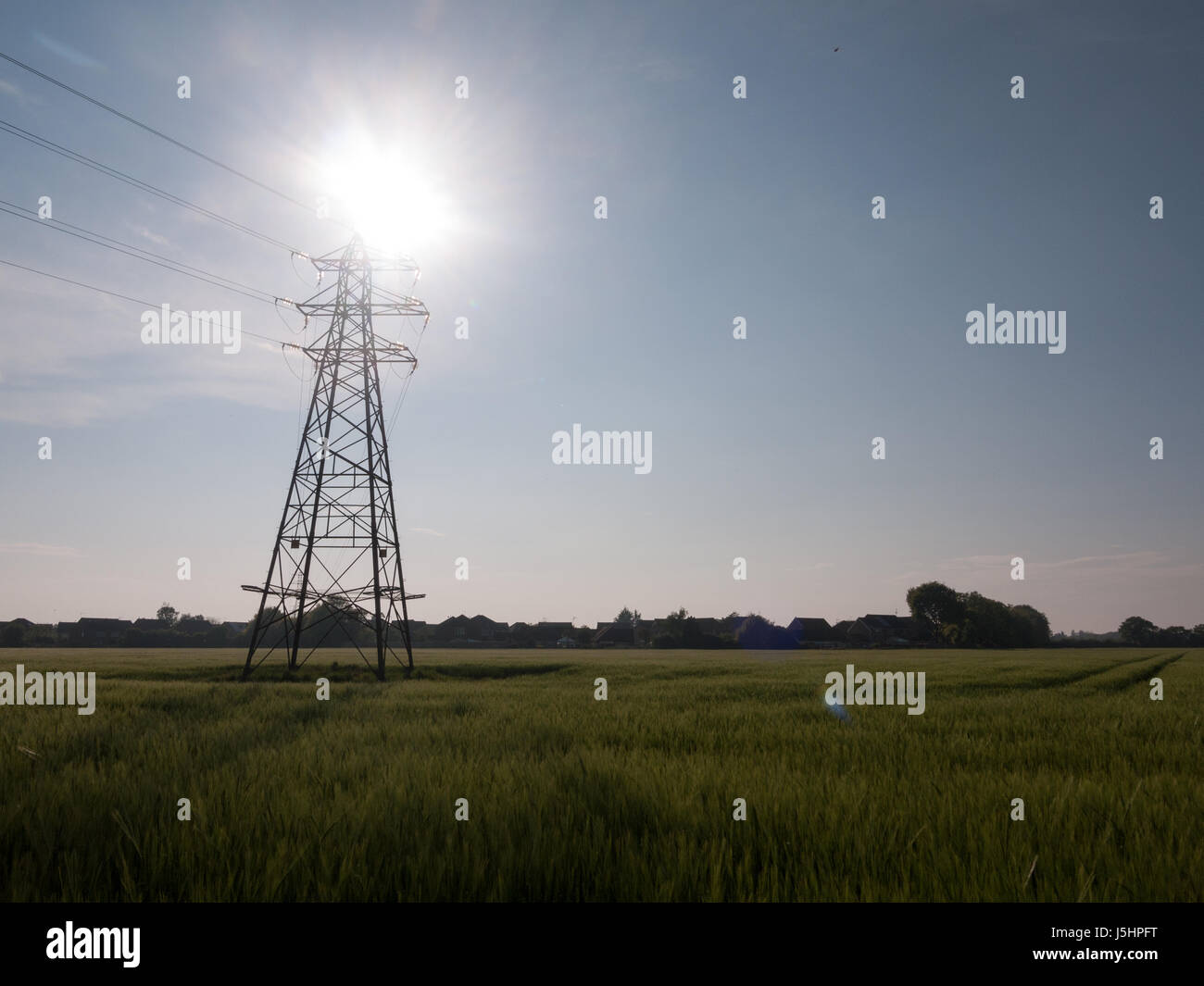 an electric pylon outside with sun behind it over field communication ...