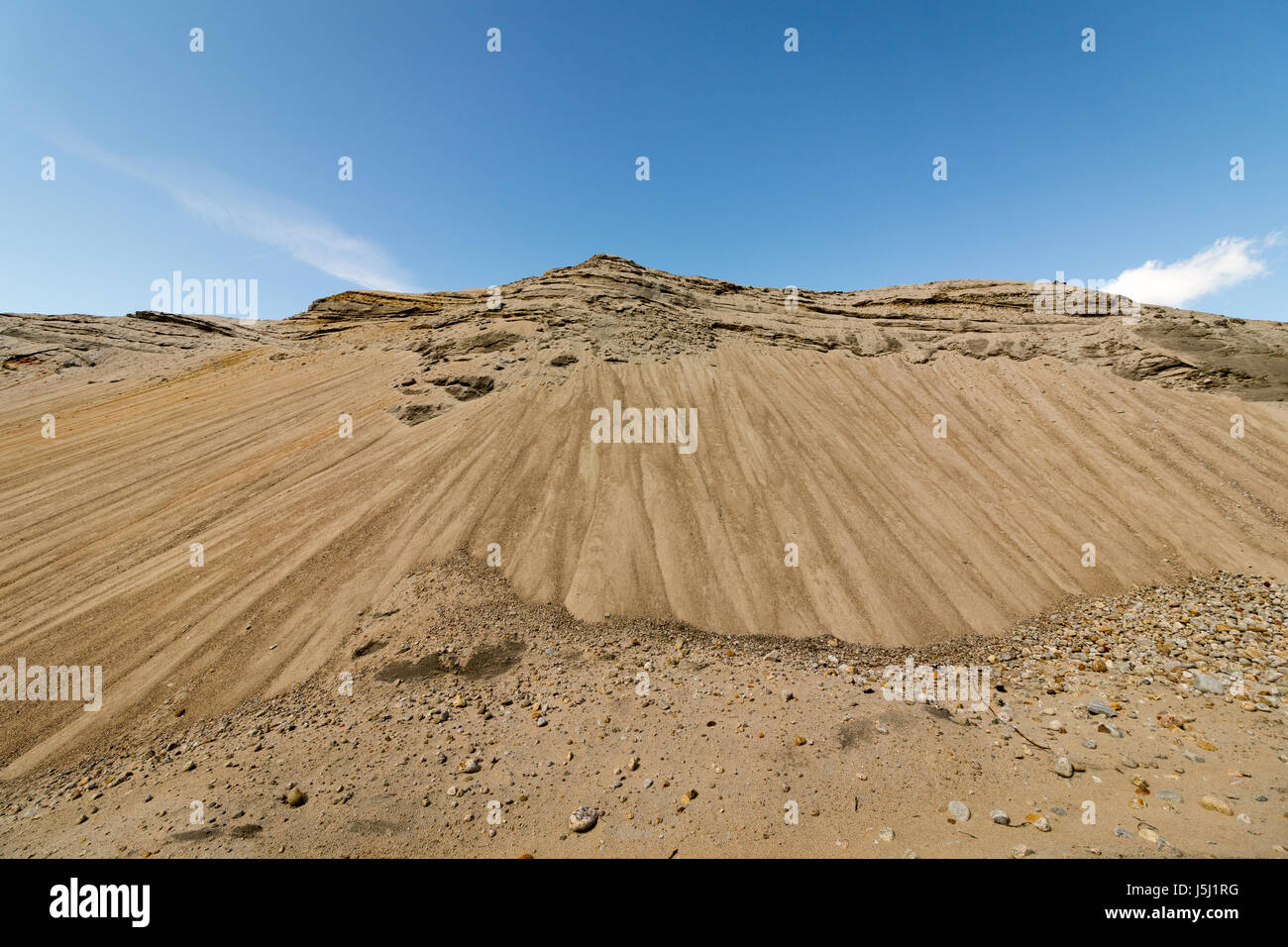 hills of sand and stone in a sand pit looks like a mountain. Blue sky ...