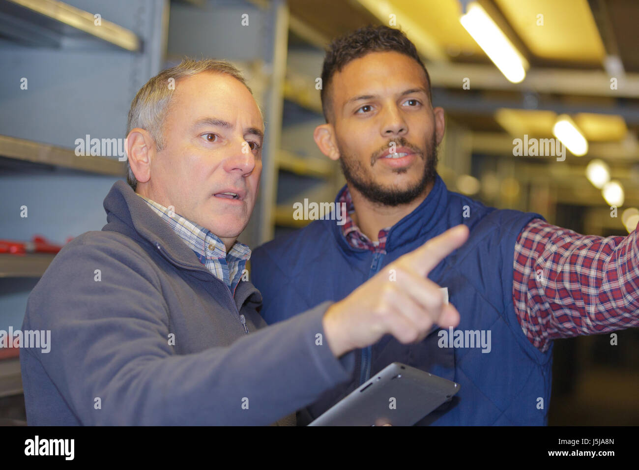 warehouse manager pointing after looking at tablet pc Stock Photo - Alamy