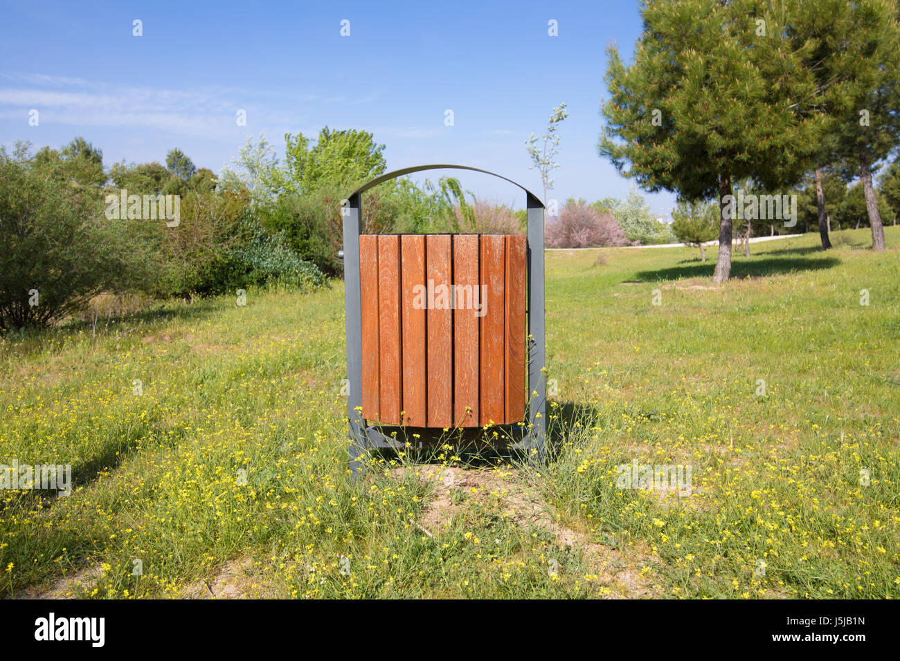 wooden and metal garbage bin, outdoors in grass meadow with flowers and ...