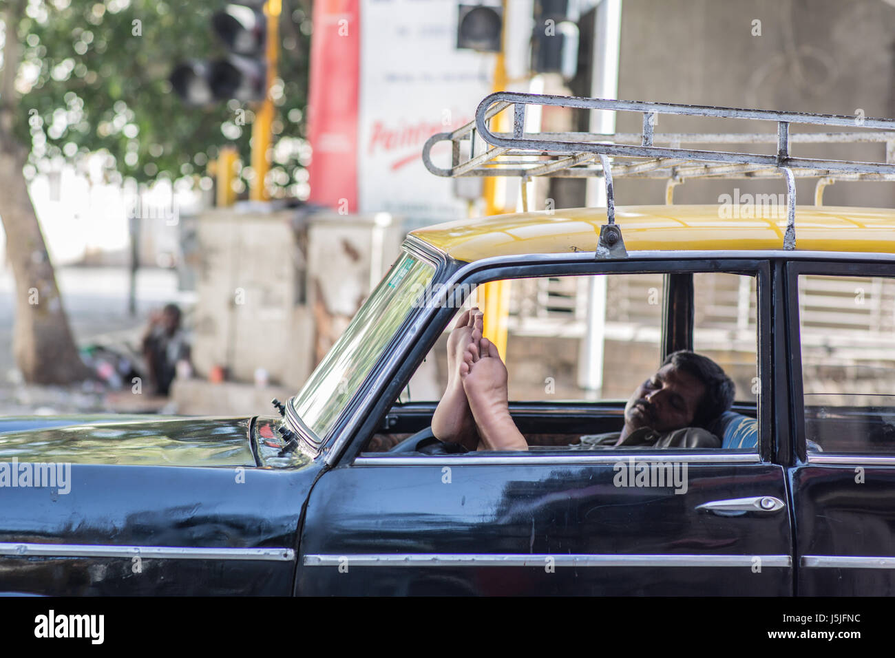 A taxi driver in Mumbai taking a lunch break and sleeping in his taxi ...