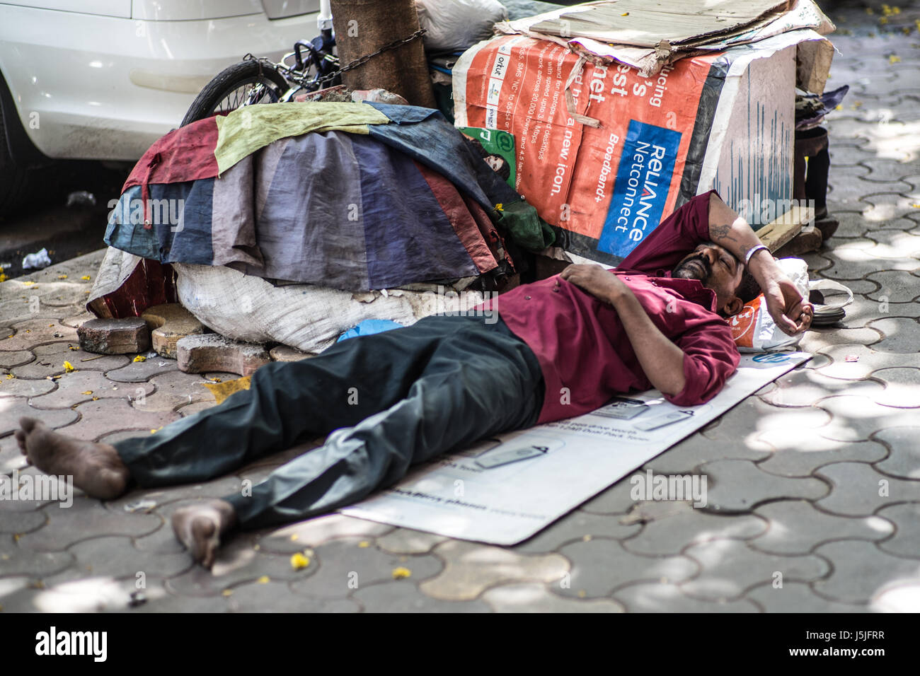 A man sleeping in the middle of the day on the ground on a street in ...