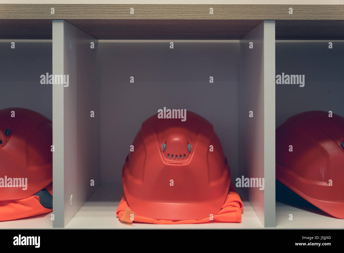 Three orange safety helmets on the shelf in locker Stock Photo - Alamy