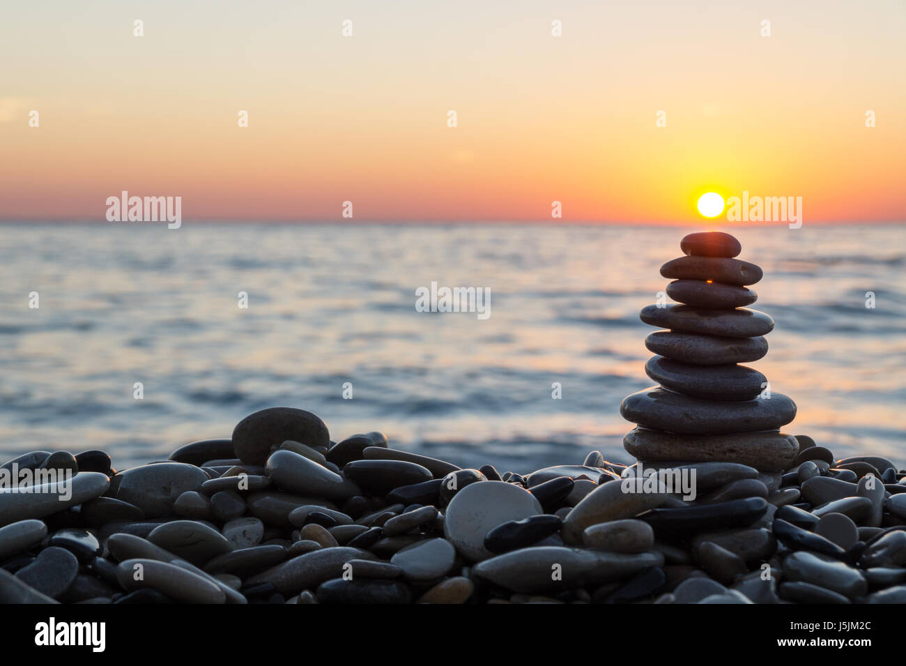 Cairn stones stacked with sun on the stony beach on sunset Stock Photo ...