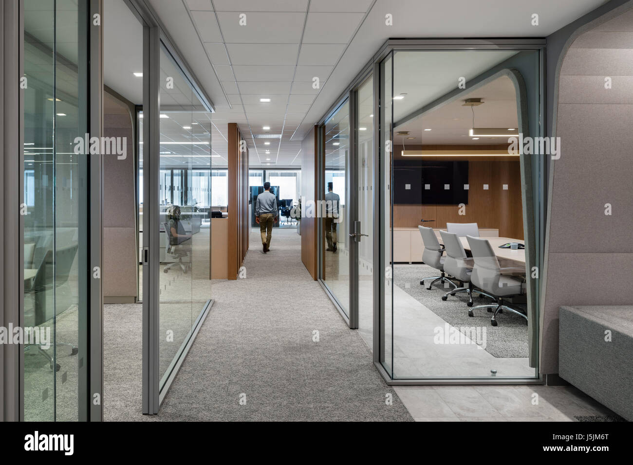 Glass enclosed conference rooms along a corridor leading the the open ...