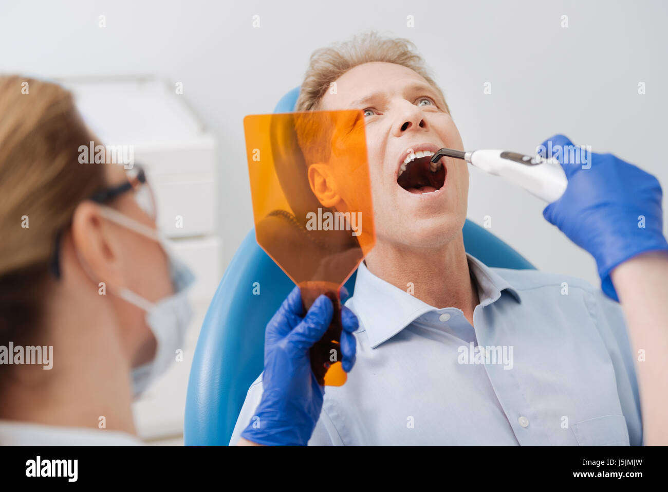 Attractive man visiting dentist for special procedure Stock Photo - Alamy