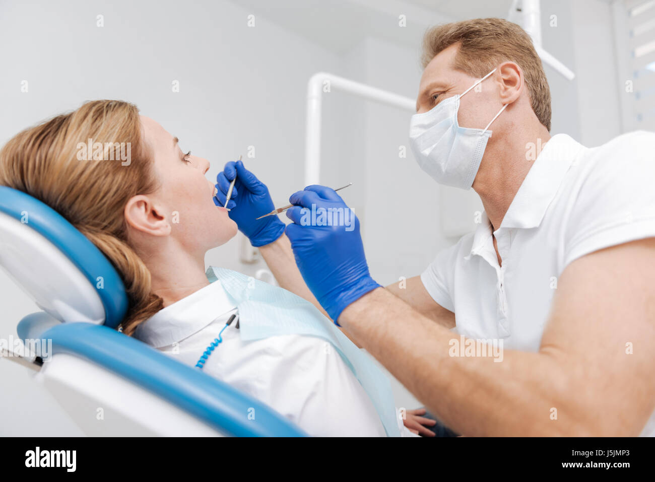Concentrated skillful dentist performing dental checkup Stock Photo - Alamy