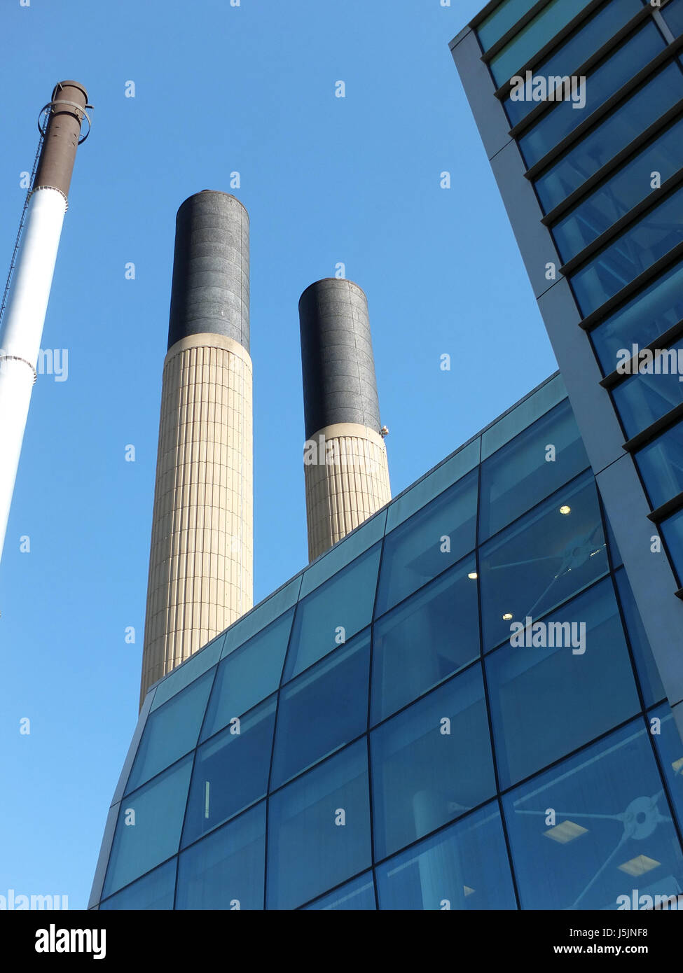 modern industrial building with glass windows and chimneys and blue sky ...