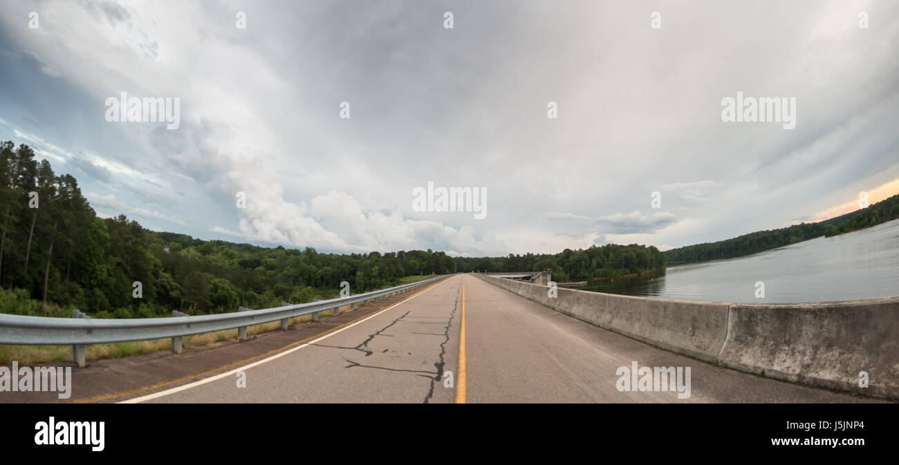Wide angle of road through forest with lake on the right Stock Photo ...