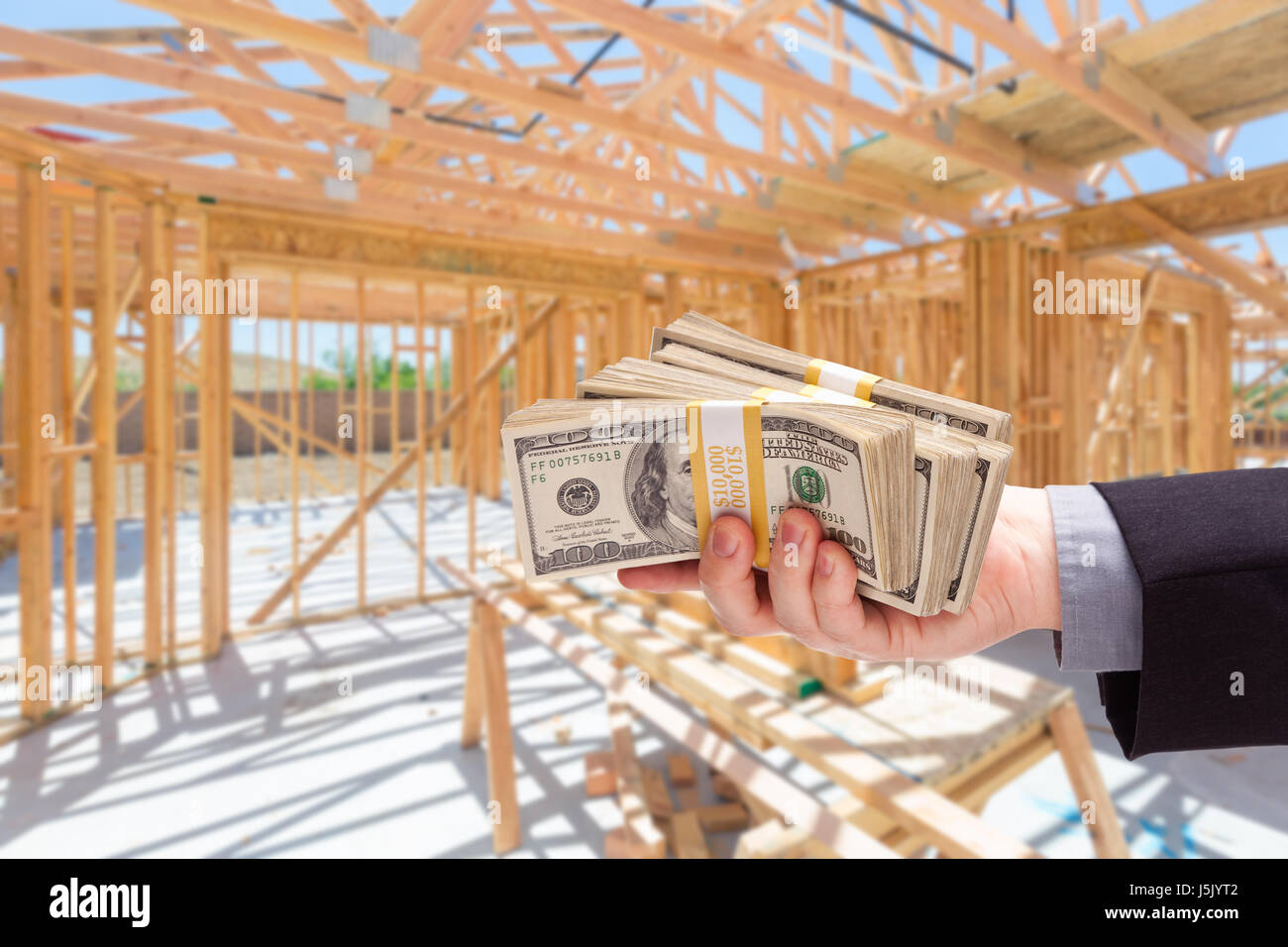 Hand With Stacks of Cash On Site Inside New Home Construction Framing ...
