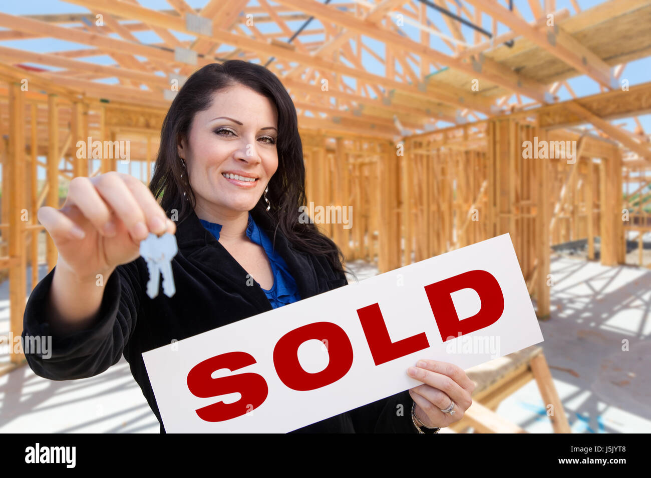 Hispanic Woman With Keys and Sold Sign On Site Inside New Home ...