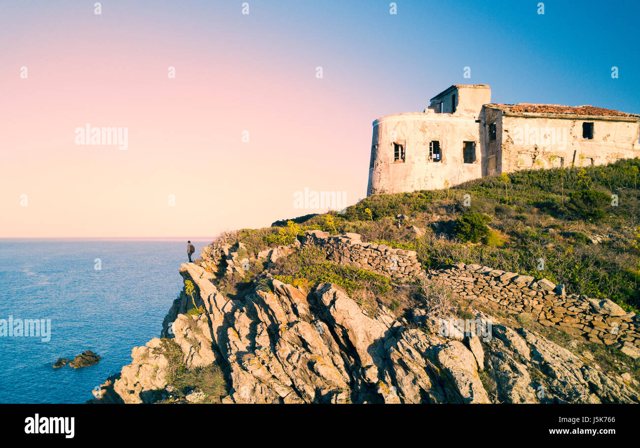 A man standing on a high cliff enjoying the view of an Italian coast ...