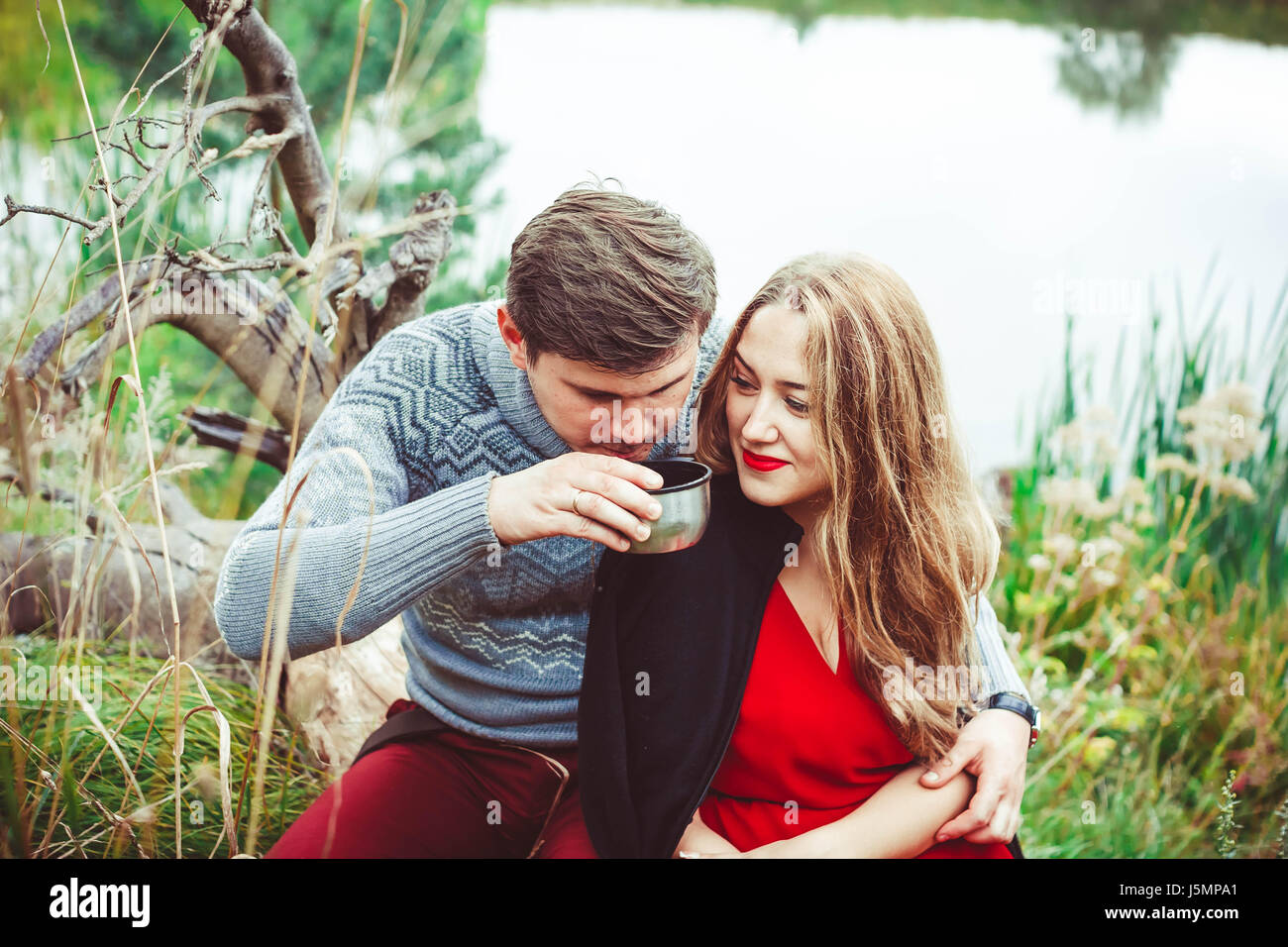 Couple drinking tea in the forest sitting on the grass Stock Photo - Alamy