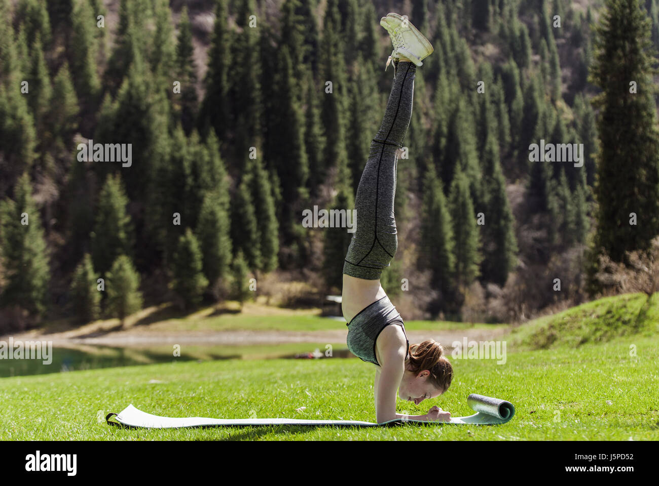 The girl on a green lawn practices yoga, pose on the head Stock Photo ...