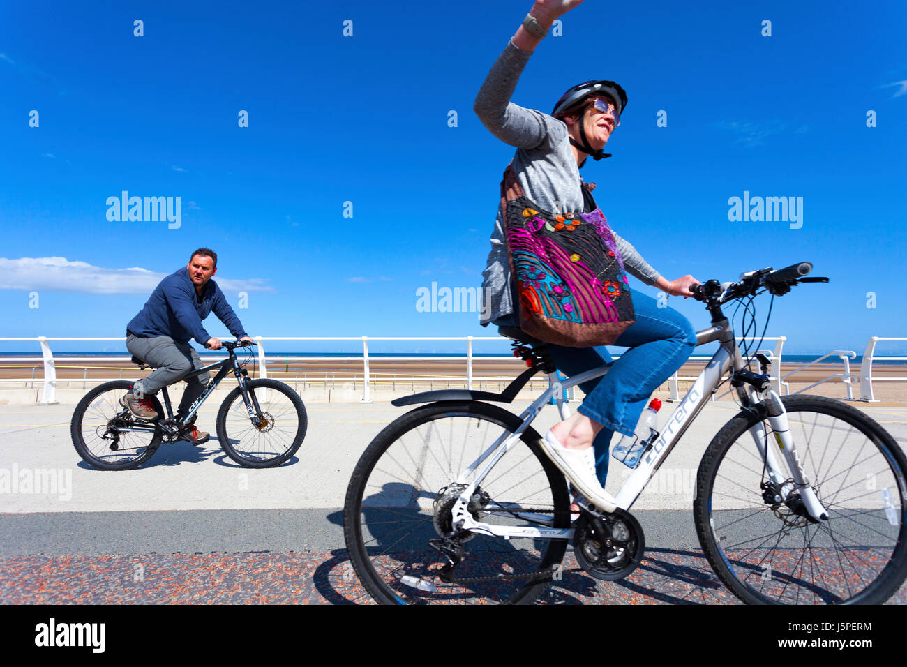 A couple taking a bike ride along the coastal promenade at the resort ...