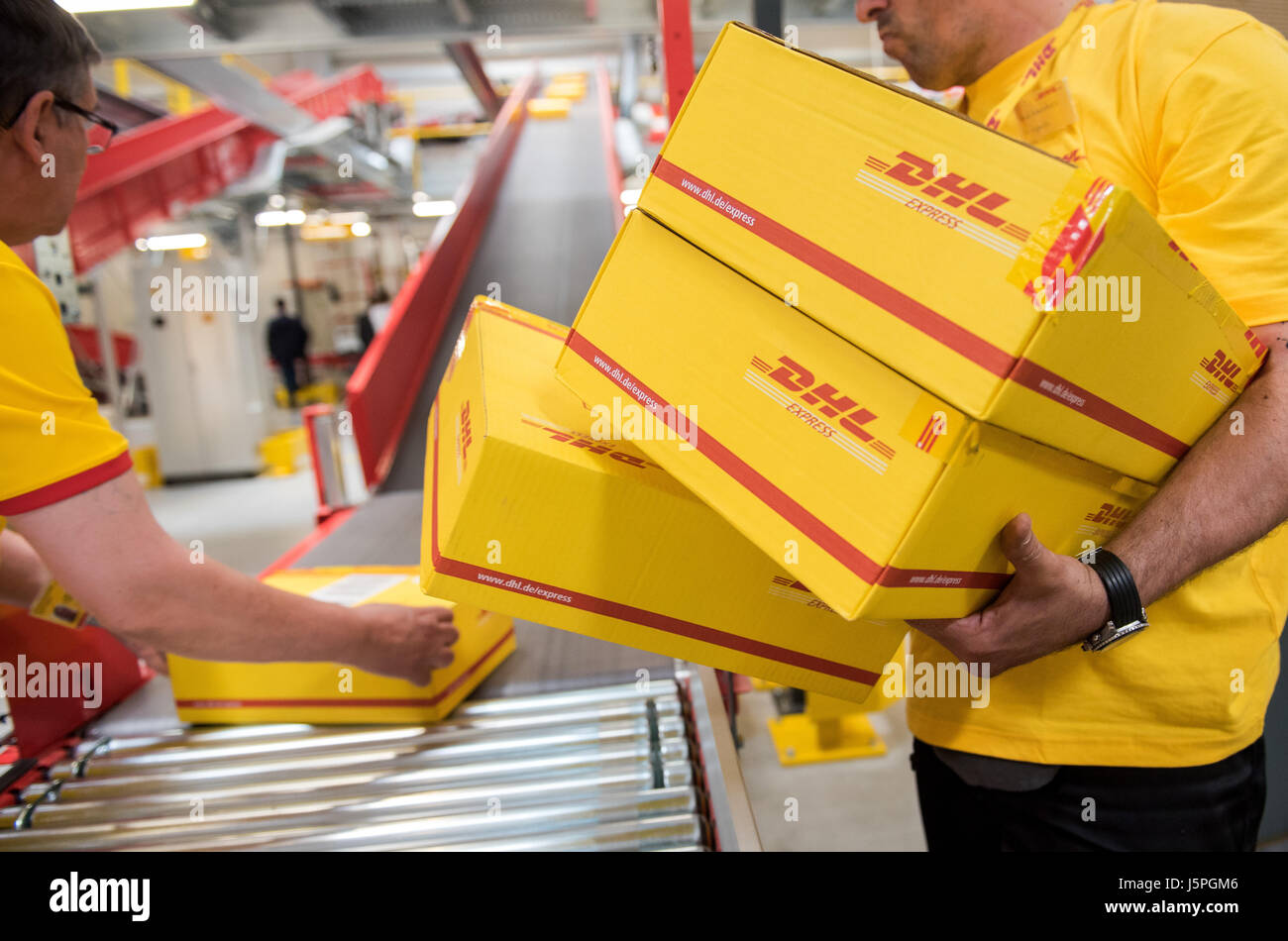 DHL staff place packages on a conveyor belt at an Express station in ...