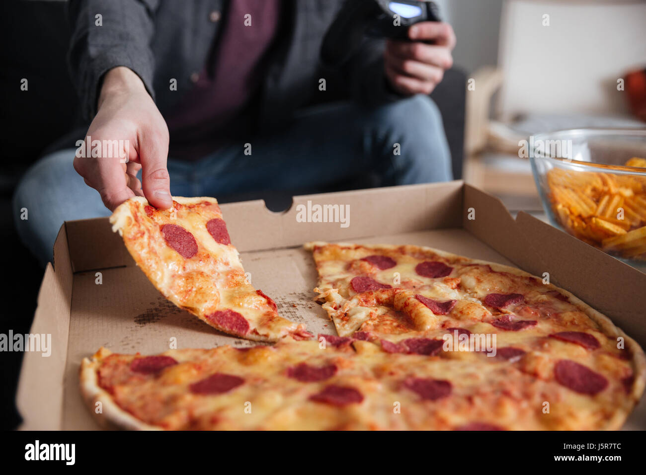 Cropped image of young man gamer sitting at home indoors and play games ...