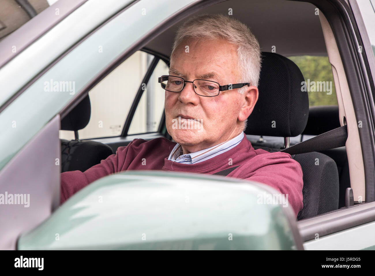 Older gentleman, senior, pensioner, over 75 years old, drives his car ...