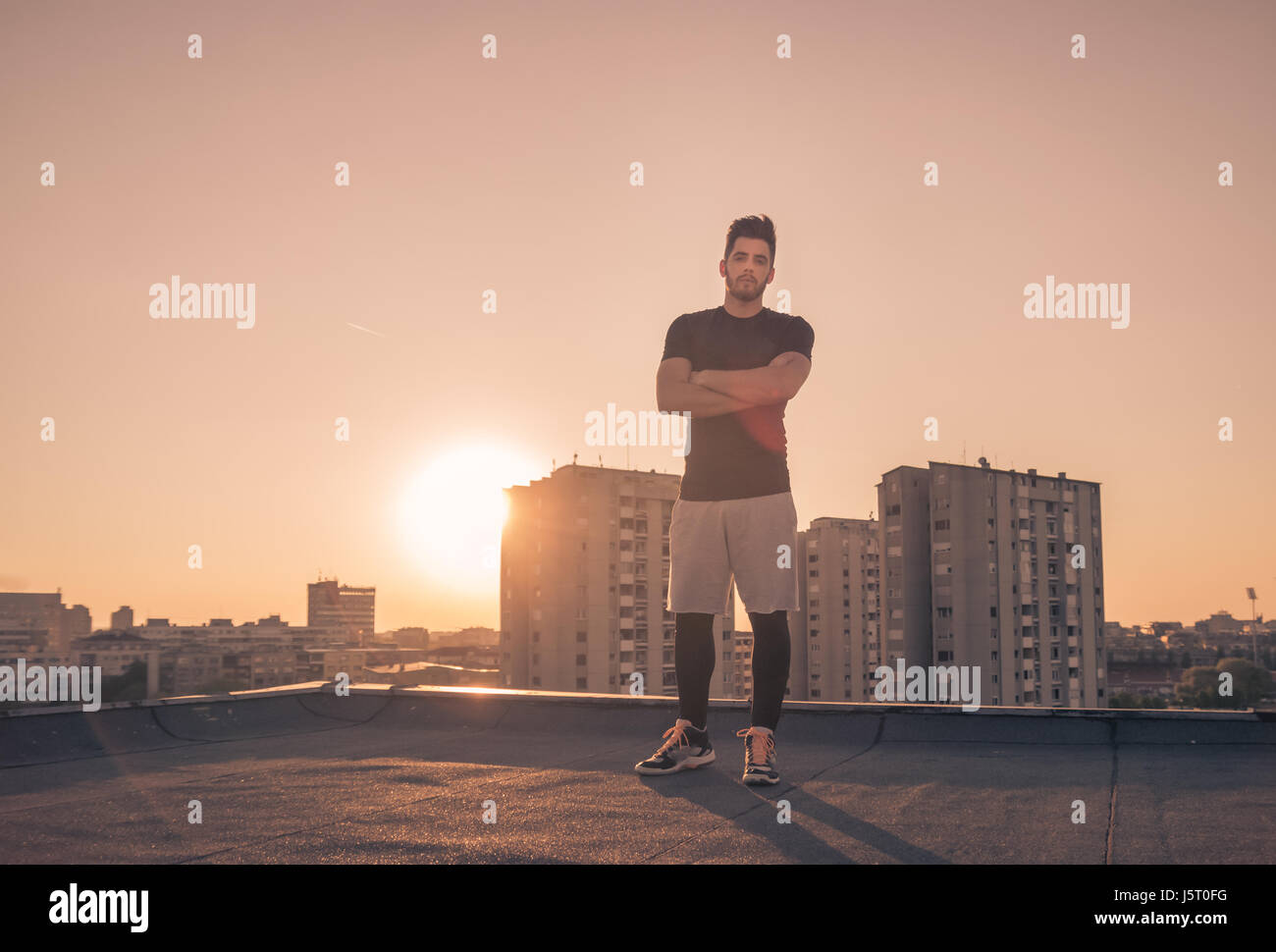 Man standing posing on rooftop buildings behind, sunrise sunset Sun sky ...