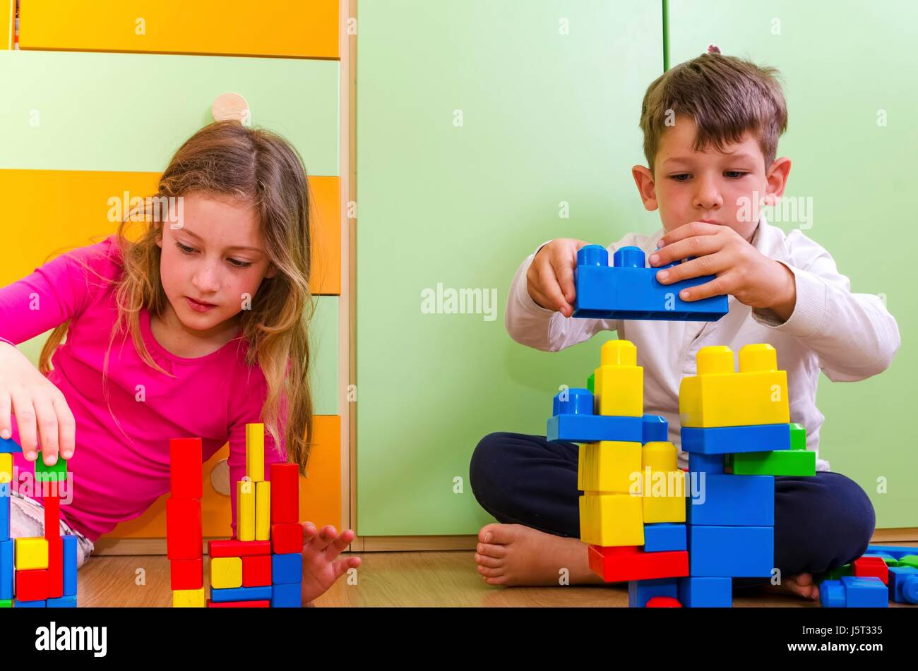 Children playing with construction toy blocks on floor of house Stock ...