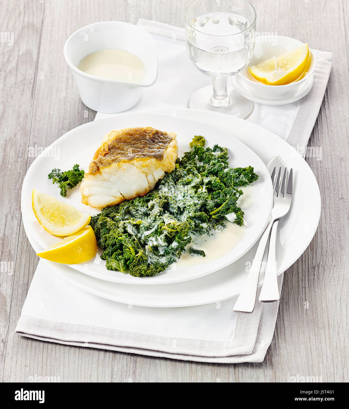 Fish filet with kale in white wine sauce Stock Photo - Alamy