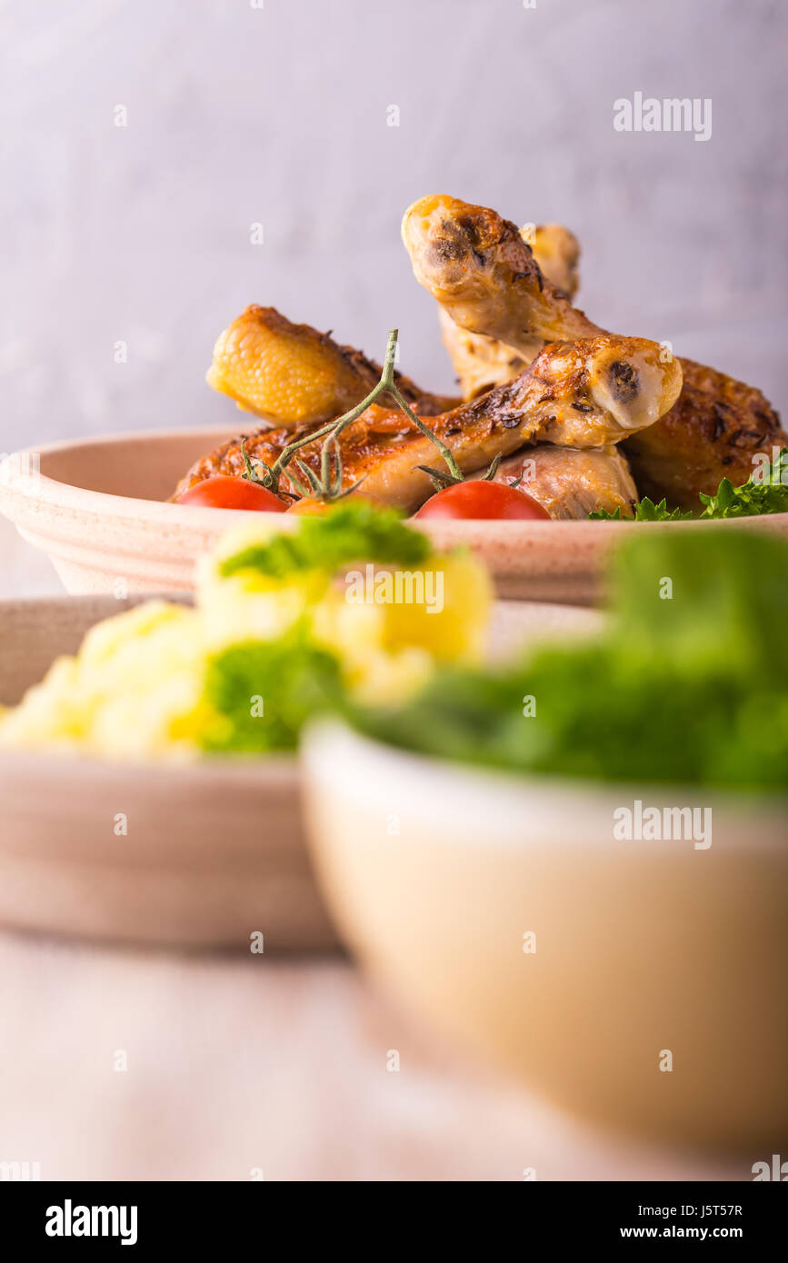 Vertical photo with baked or fried chicken legs on clay plate. Food is ...