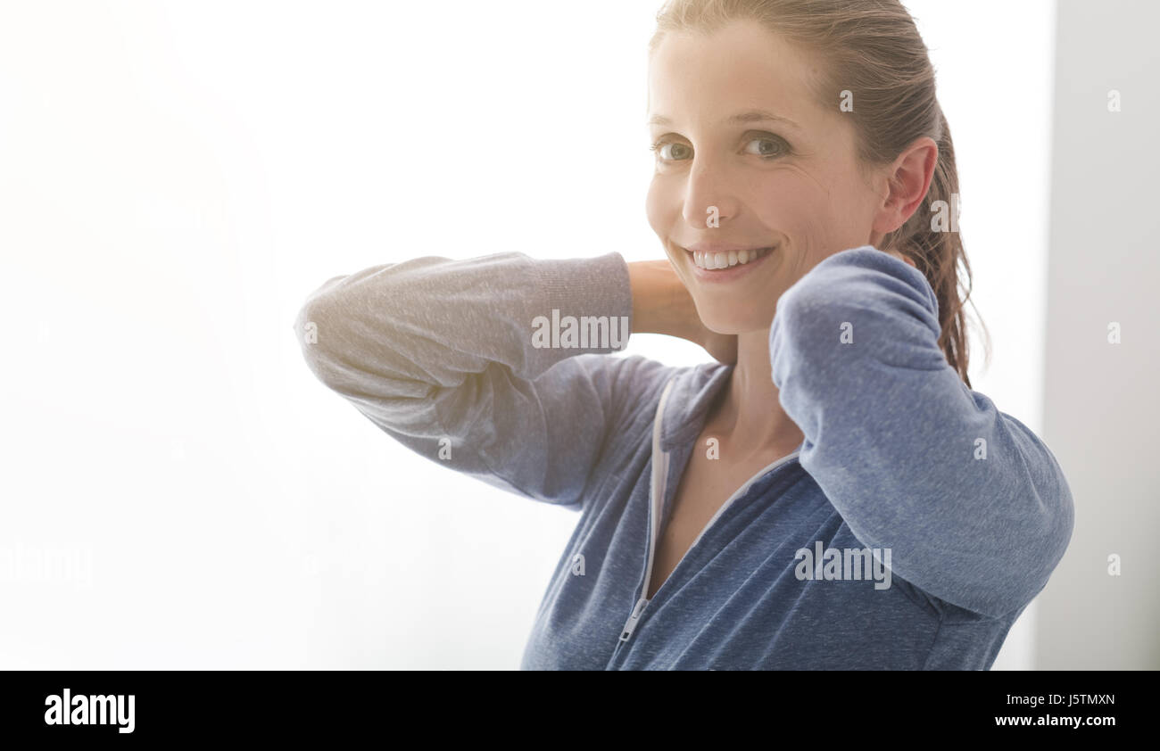 Attractive woman posing and smiling at camera, she is touching her neck ...