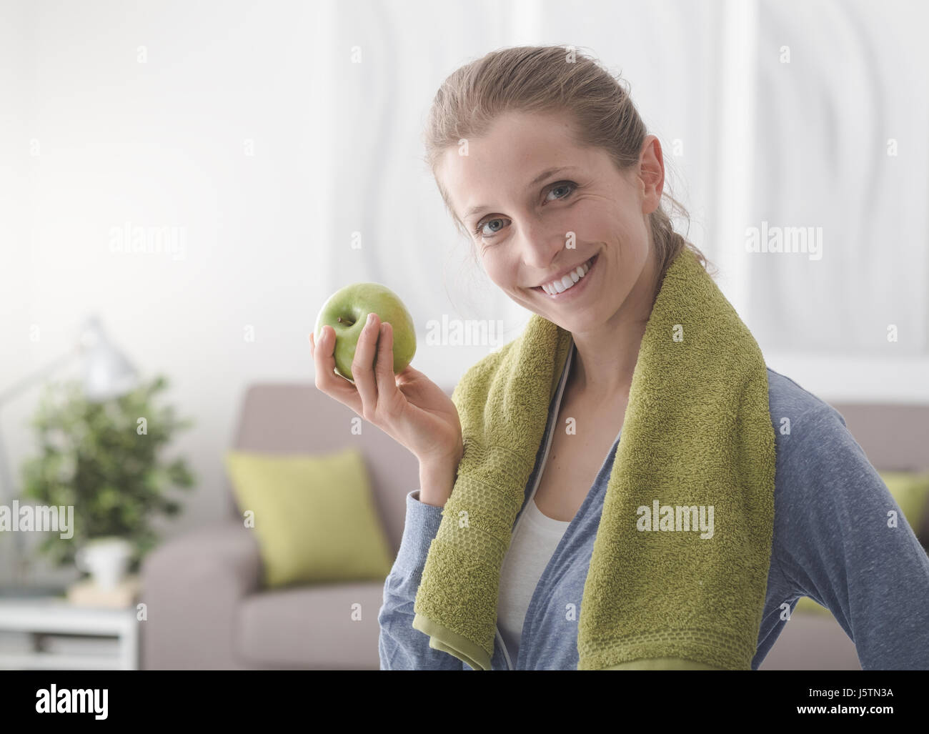 Confident smiling woman eating an apple after working out, fitness and ...