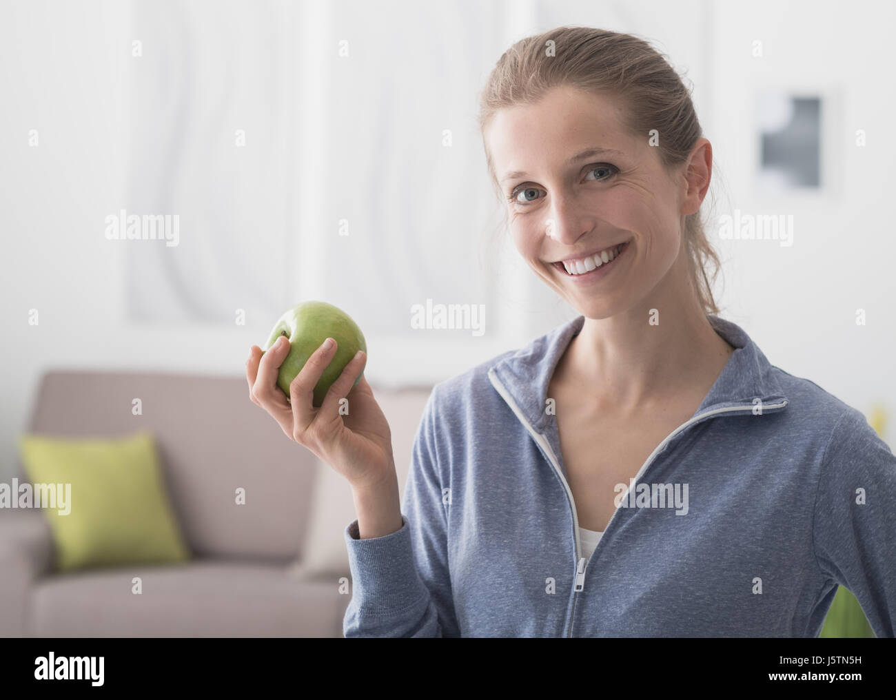 Confident smiling woman eating an apple after working out, fitness and ...