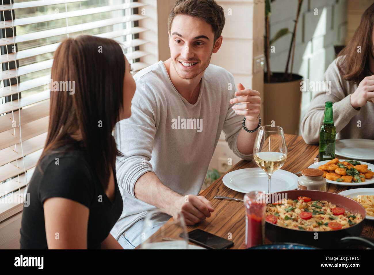 Happy young couple eating and talking at the table at home Stock Photo ...