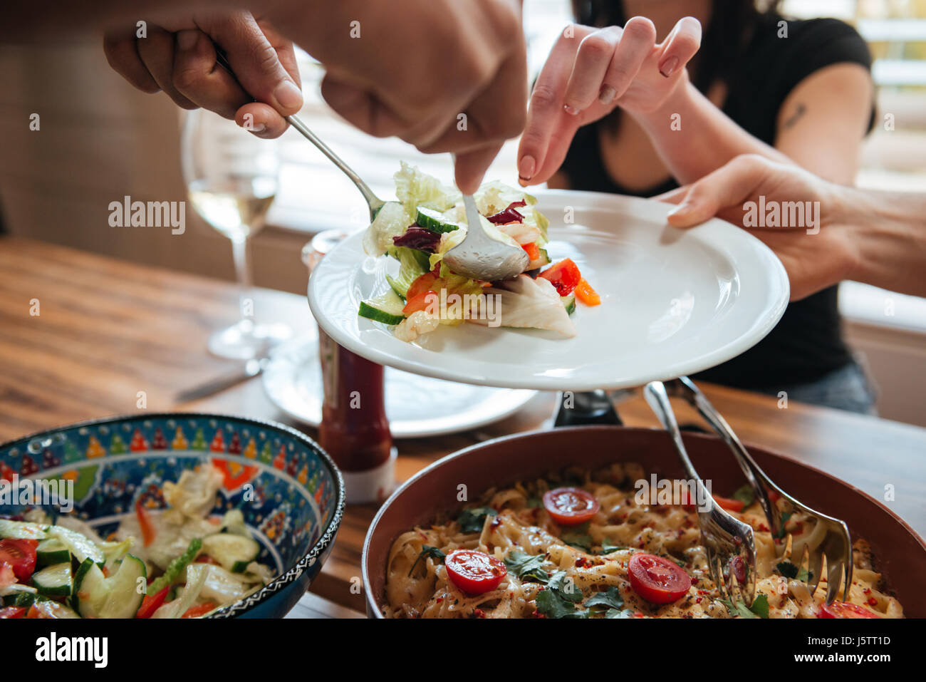 Closeup of people putting food on the plate and having dinner together ...