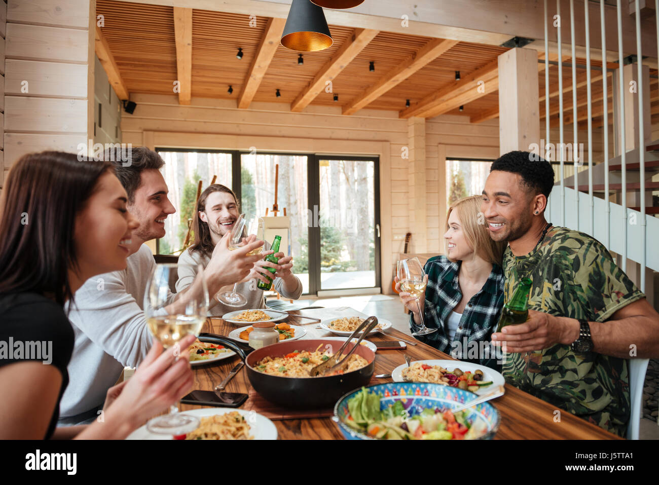 Group of cheerful young friends having dinner and laughing at the table ...