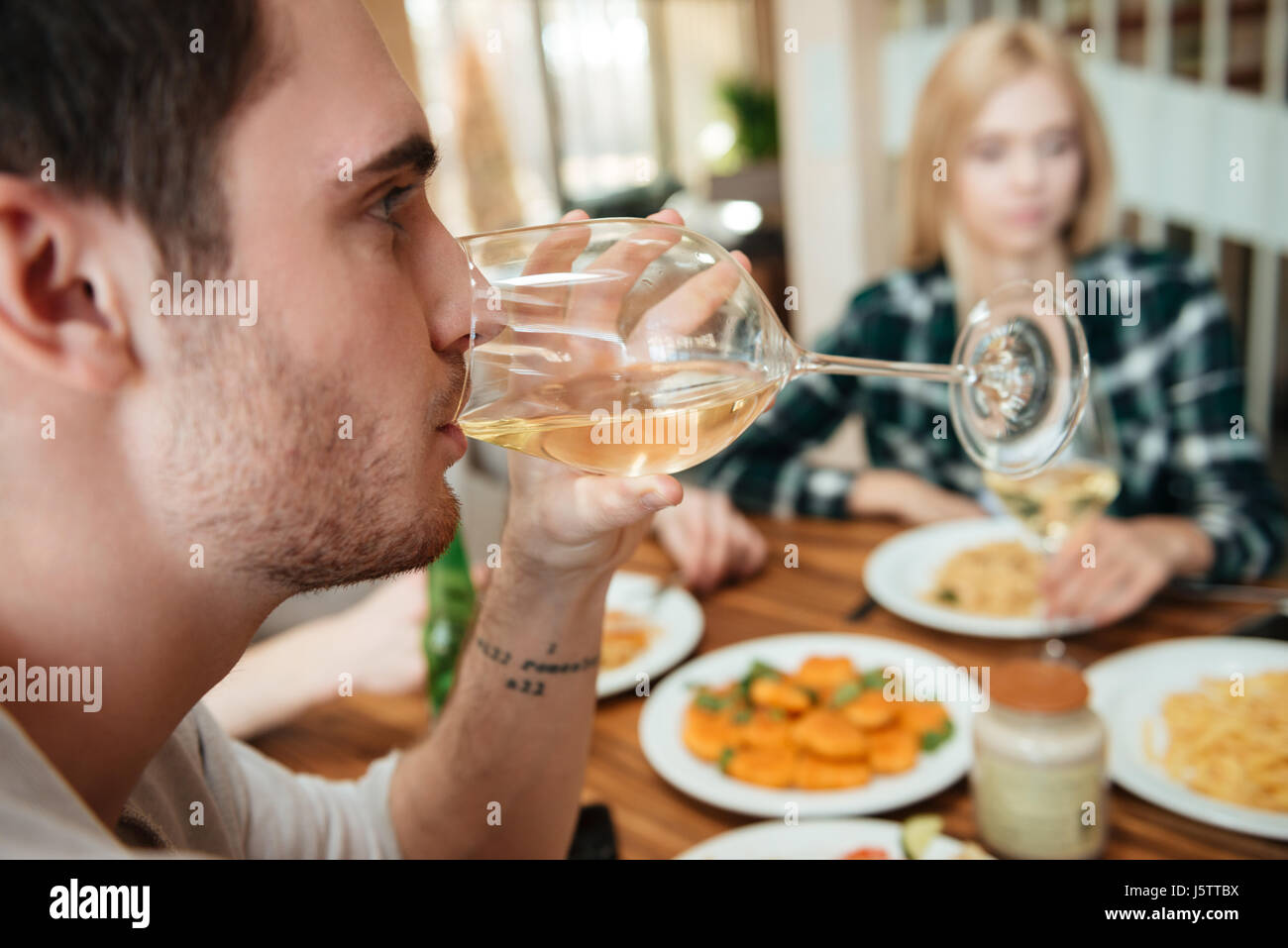 Closeup of handsome young man having dinner and drinking wine with ...