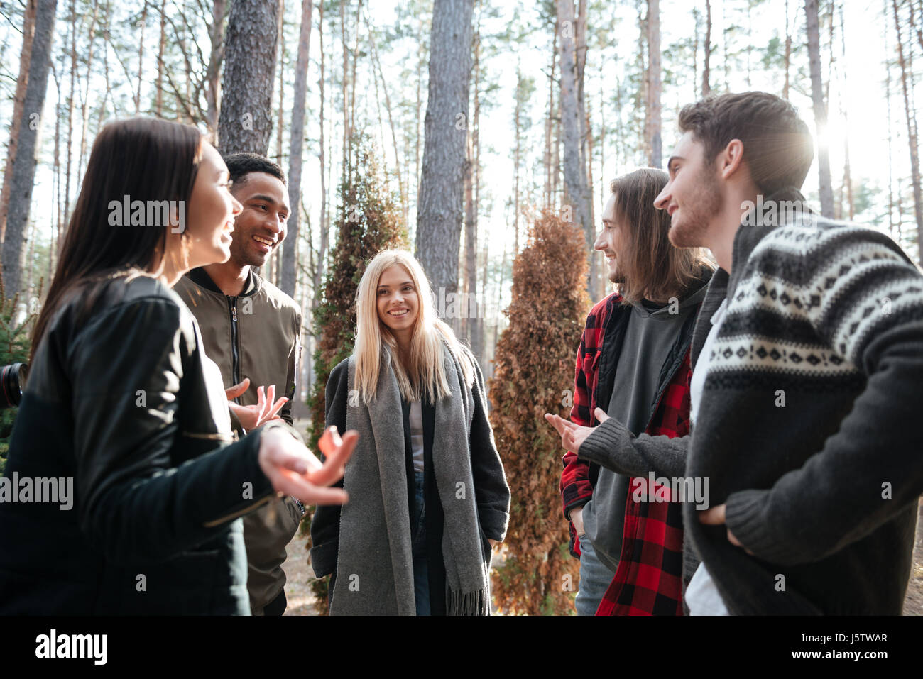 Image of happy group of friends standing outdoors in the forest looking ...