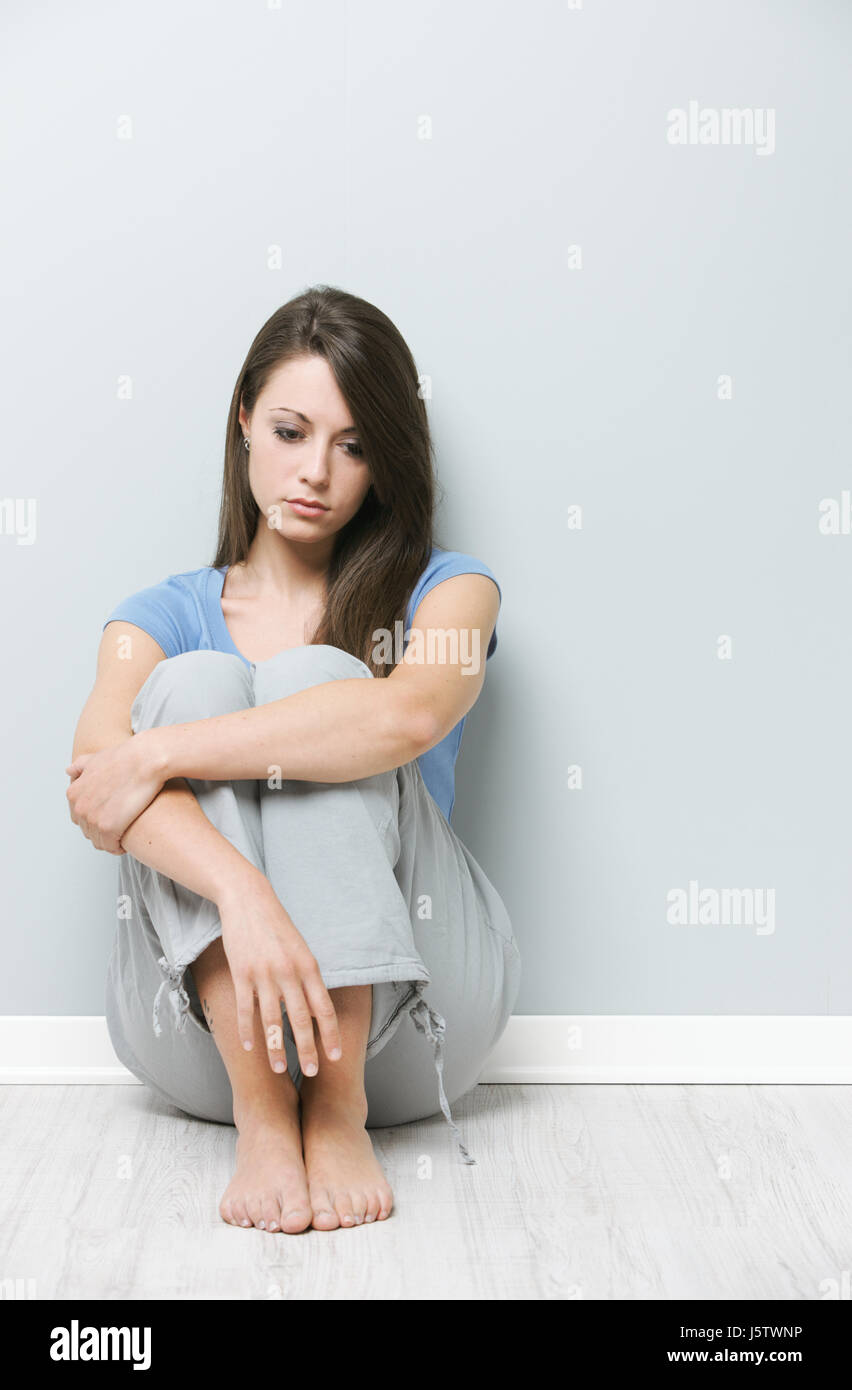 Young sad woman sitting on floor at home Stock Photo - Alamy