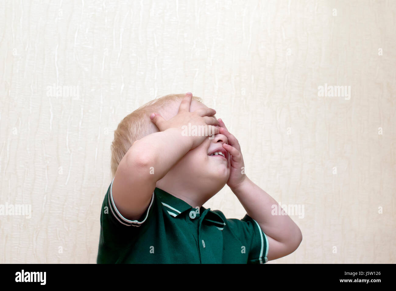 A blonde boy crying covering his face with hands, studio photo Stock ...