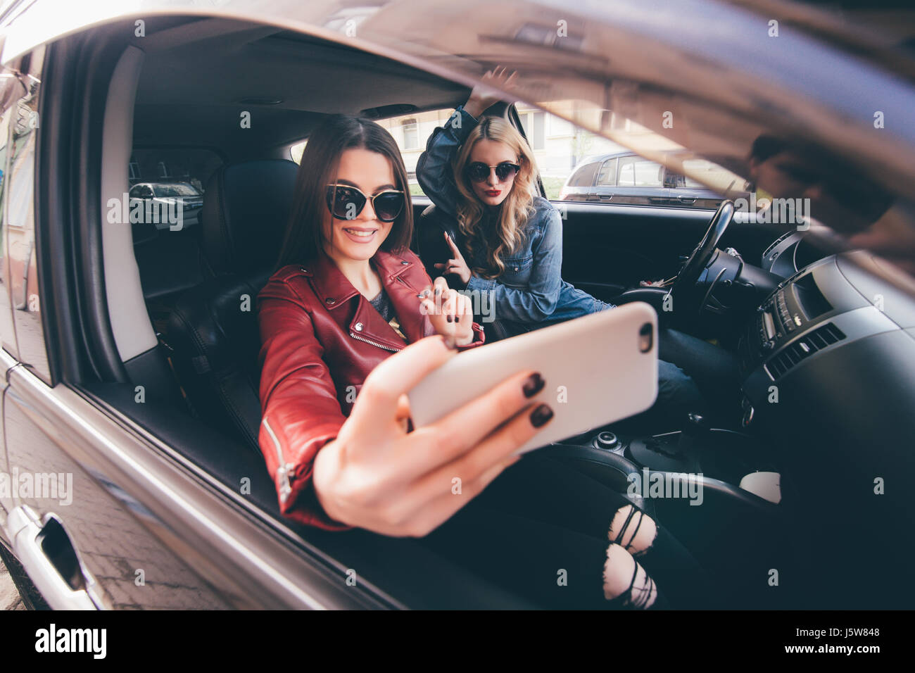 Group of girls having fun with the car. Taking selfie while driving ...